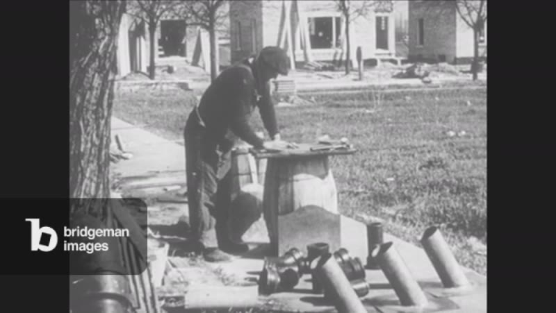Image of 1950s: Two men install a vent pipe in a house