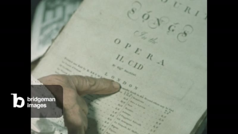 Image of 1960s: Person picks up booklet for opera, points to the